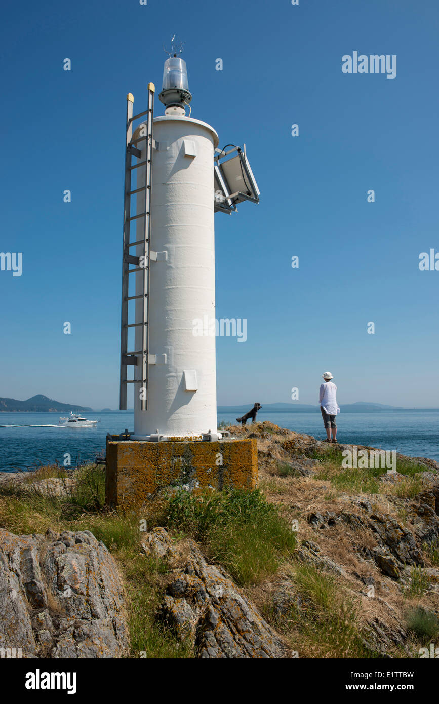 Woman and dog by marine beacon , Gulf Islands, British Columbia, Canada ...