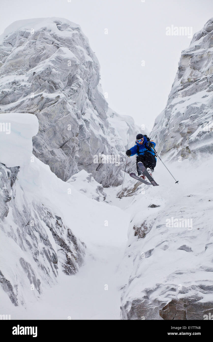 A male freeskier drops a cliff into a small chute at Revelstoke Moutain ...