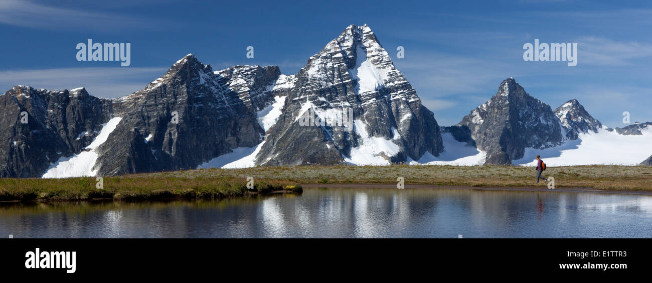 Hiker walks along alpine tarn in front of Mt Sir Donald, Glacier ...