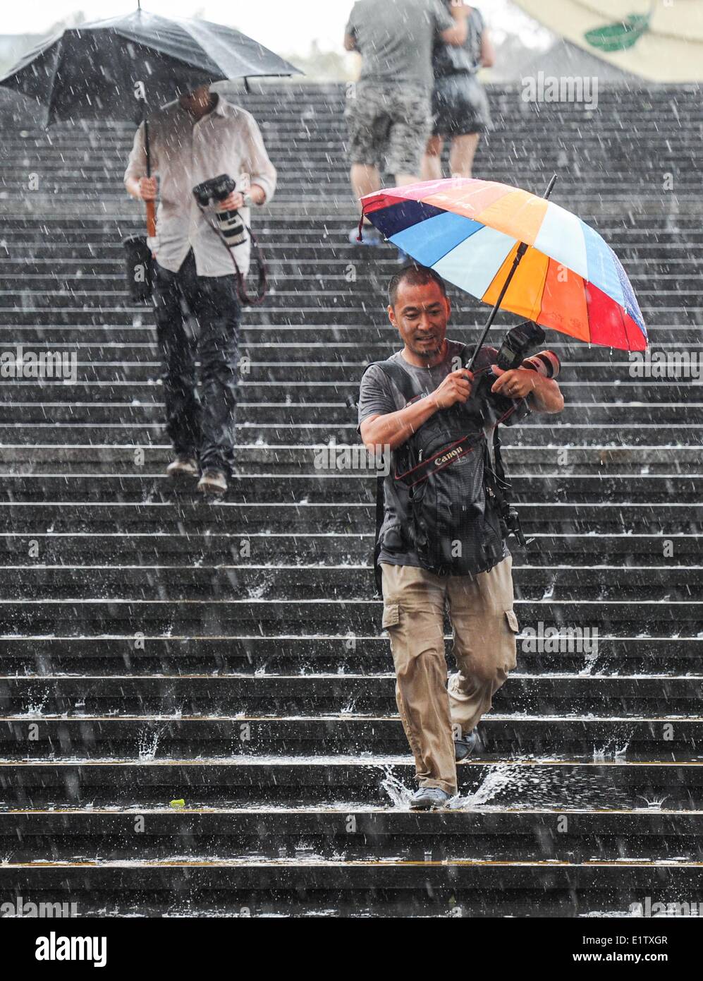 Beijing, China. 10th June, 2014. Photographers walk down steps in rain ...