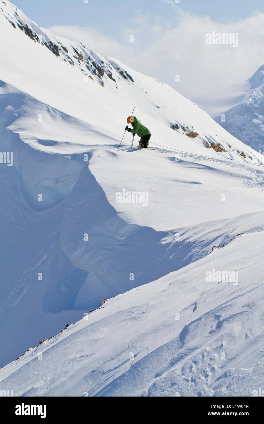 A male backcountry skier cutting a cornice to do some slope testing ...