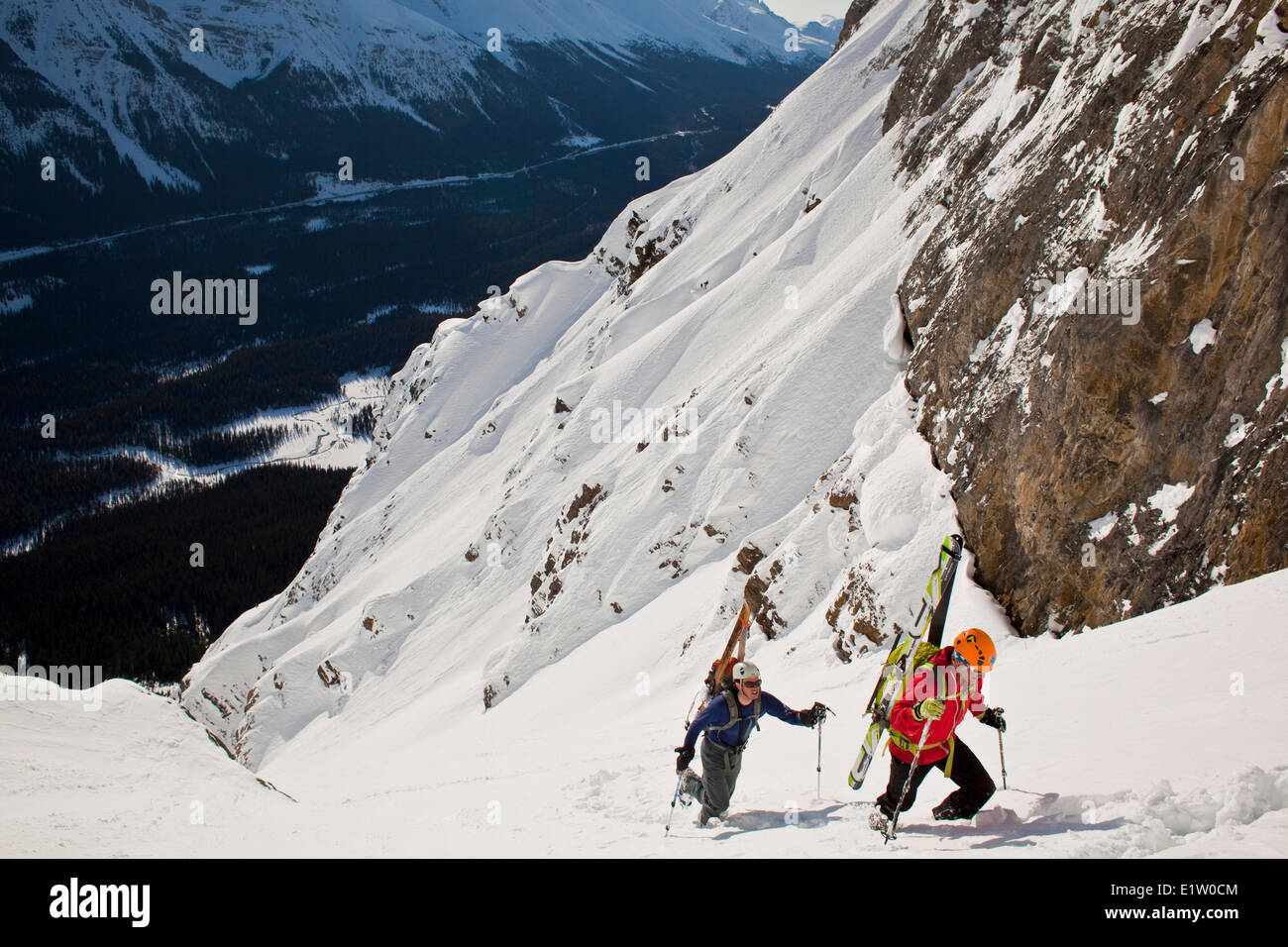 Two male backcountry skiers bootpack up a steep and exposed coulior on ...
