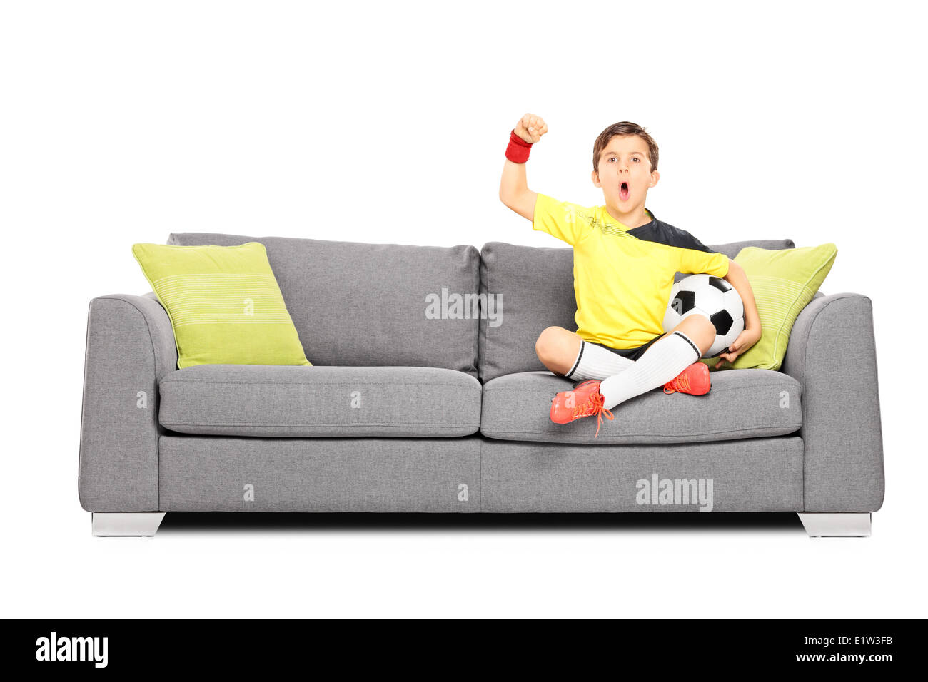 Kid cheering and holding football seated on sofa Stock Photo - Alamy