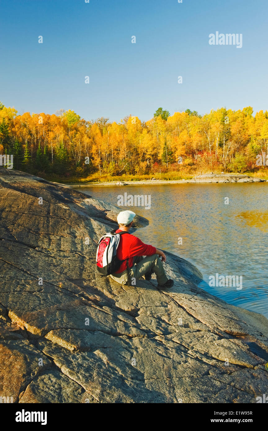 Hiker relaxes on precambrian shield rock along the winnipeg river hi ...