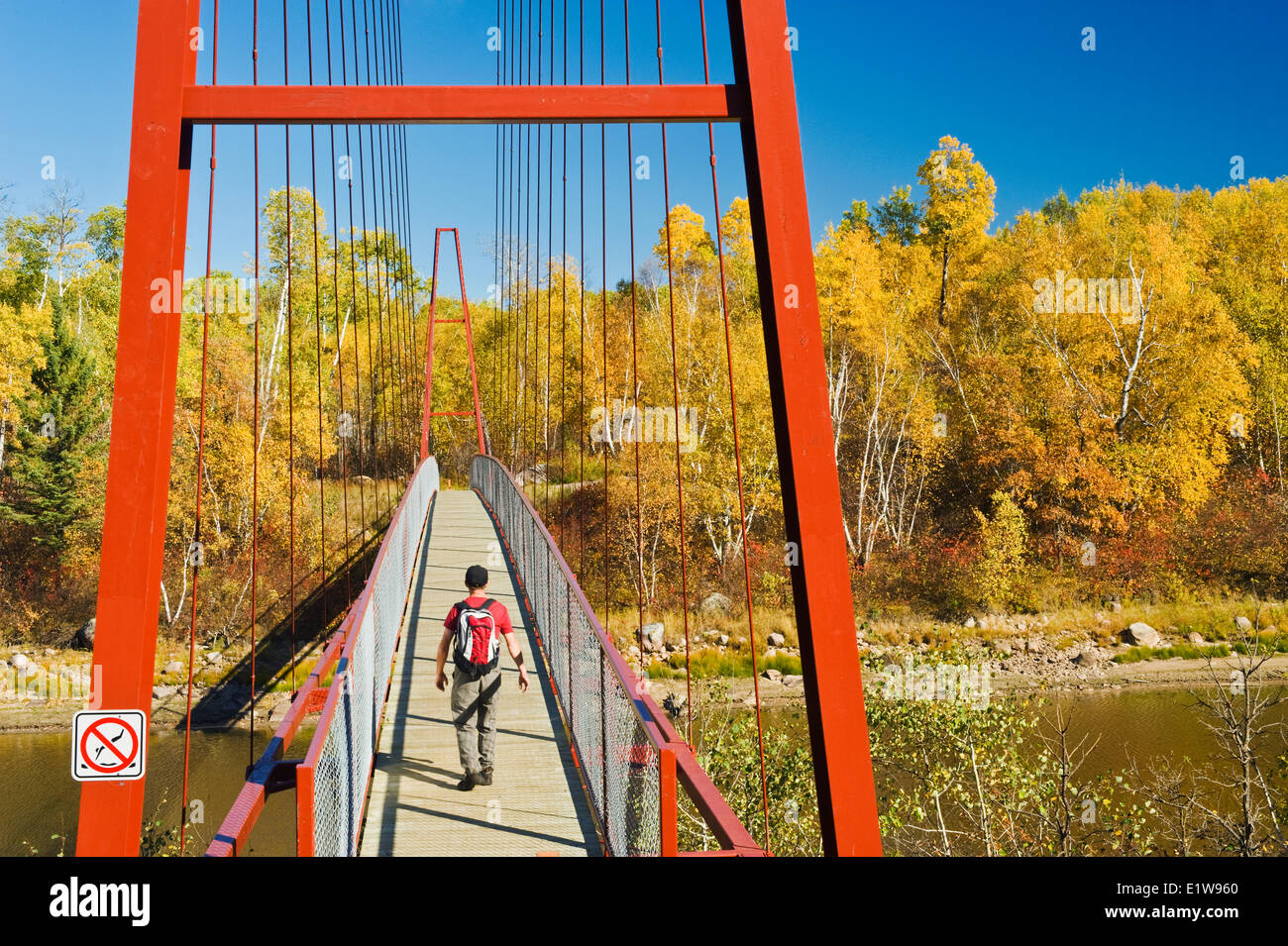 Hiker crosses a bridge over the Whiteshell River along the Trans Canada ...