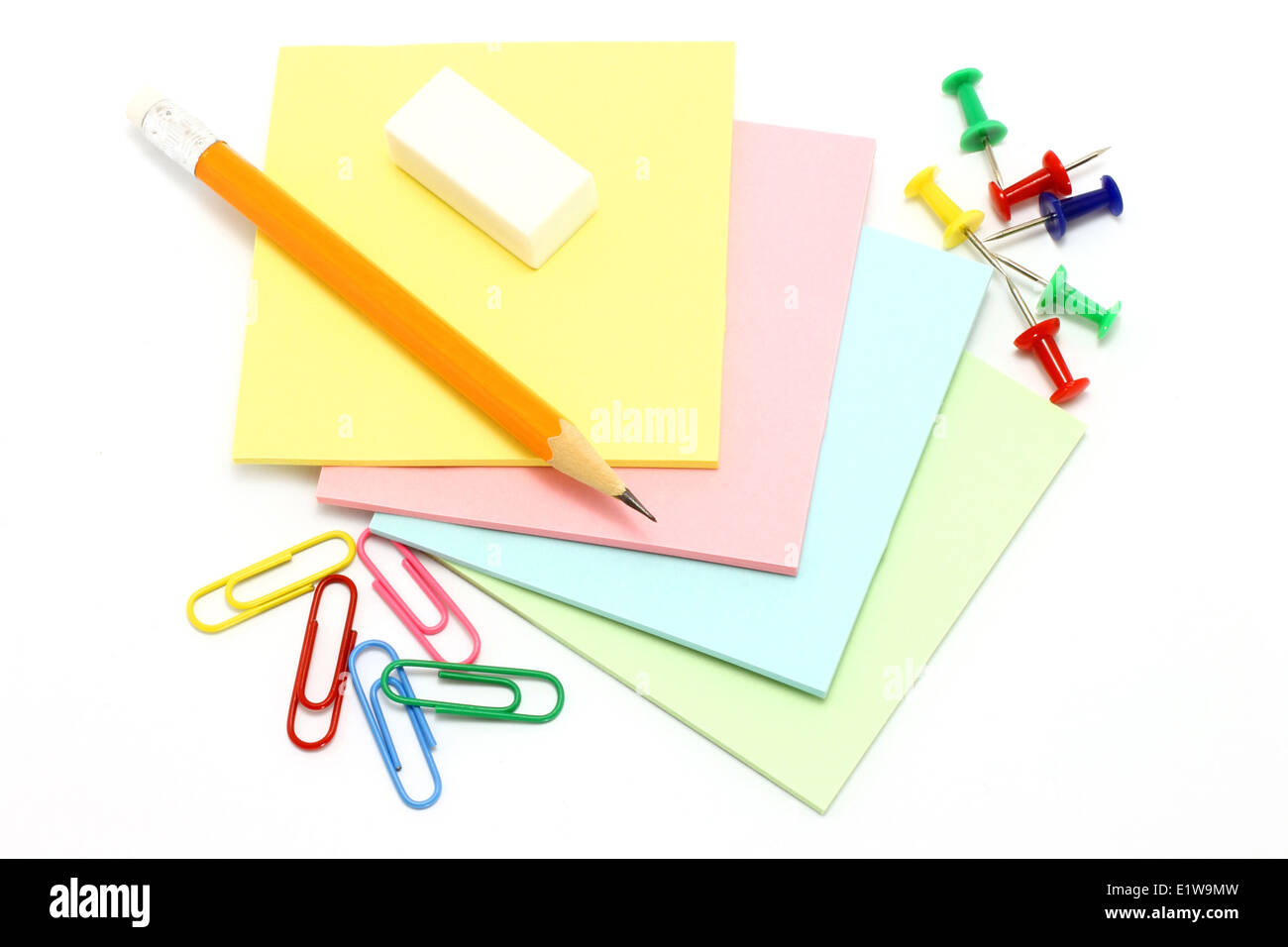 Colour paper with drawing pins and clips and pencil on a white ...