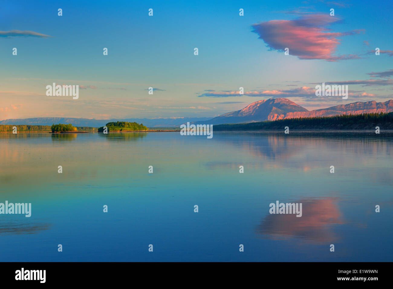 Clouds at sunrise reflecting in the Liard River and mountain of Nahanni ...