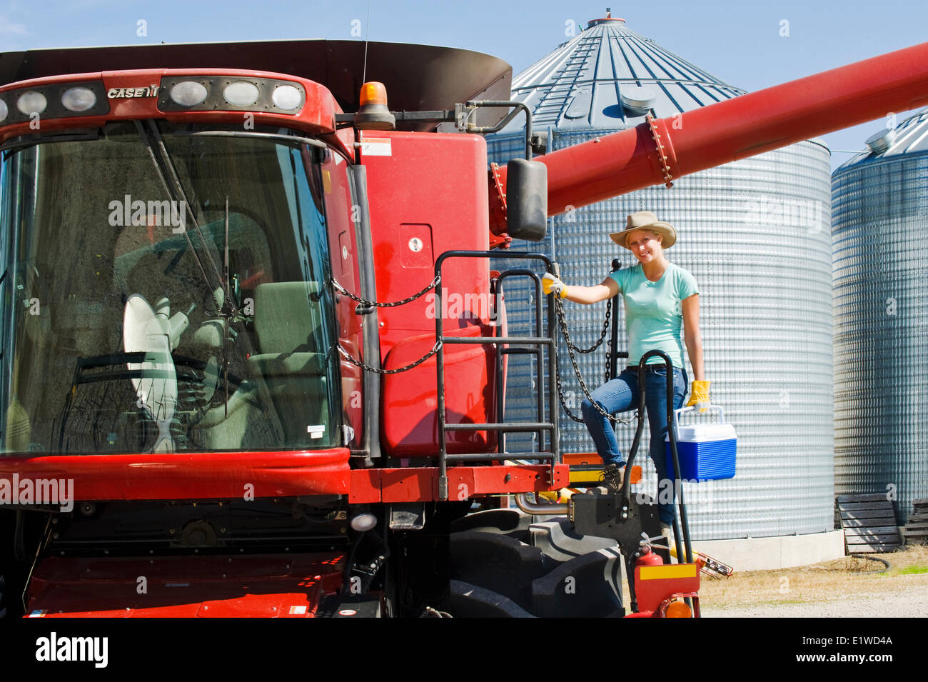 a farm girl on the deck of a combine in a farmyard prepares for a day ...