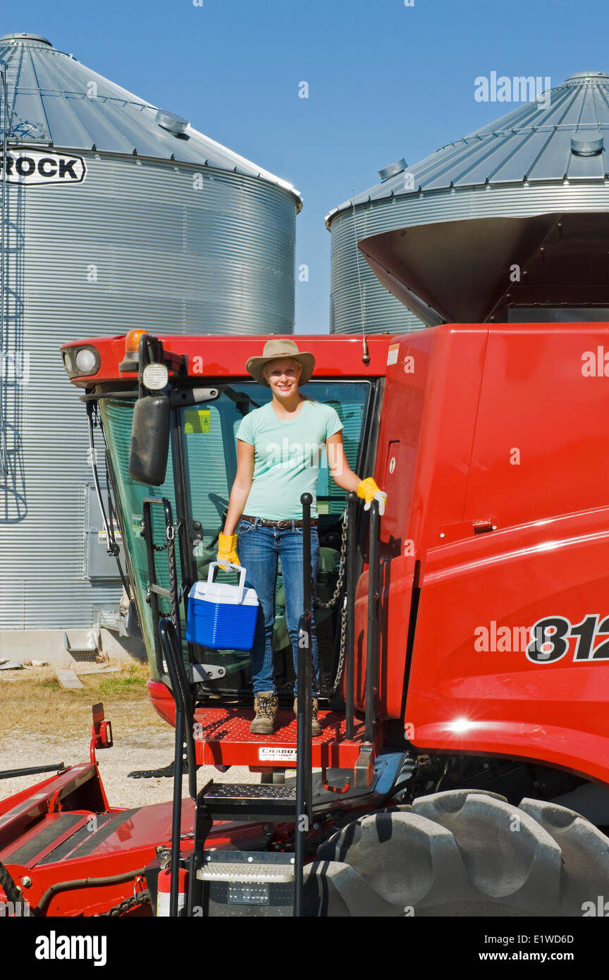 a farm girl on the deck of a combine in a farmyard prepares for a day ...