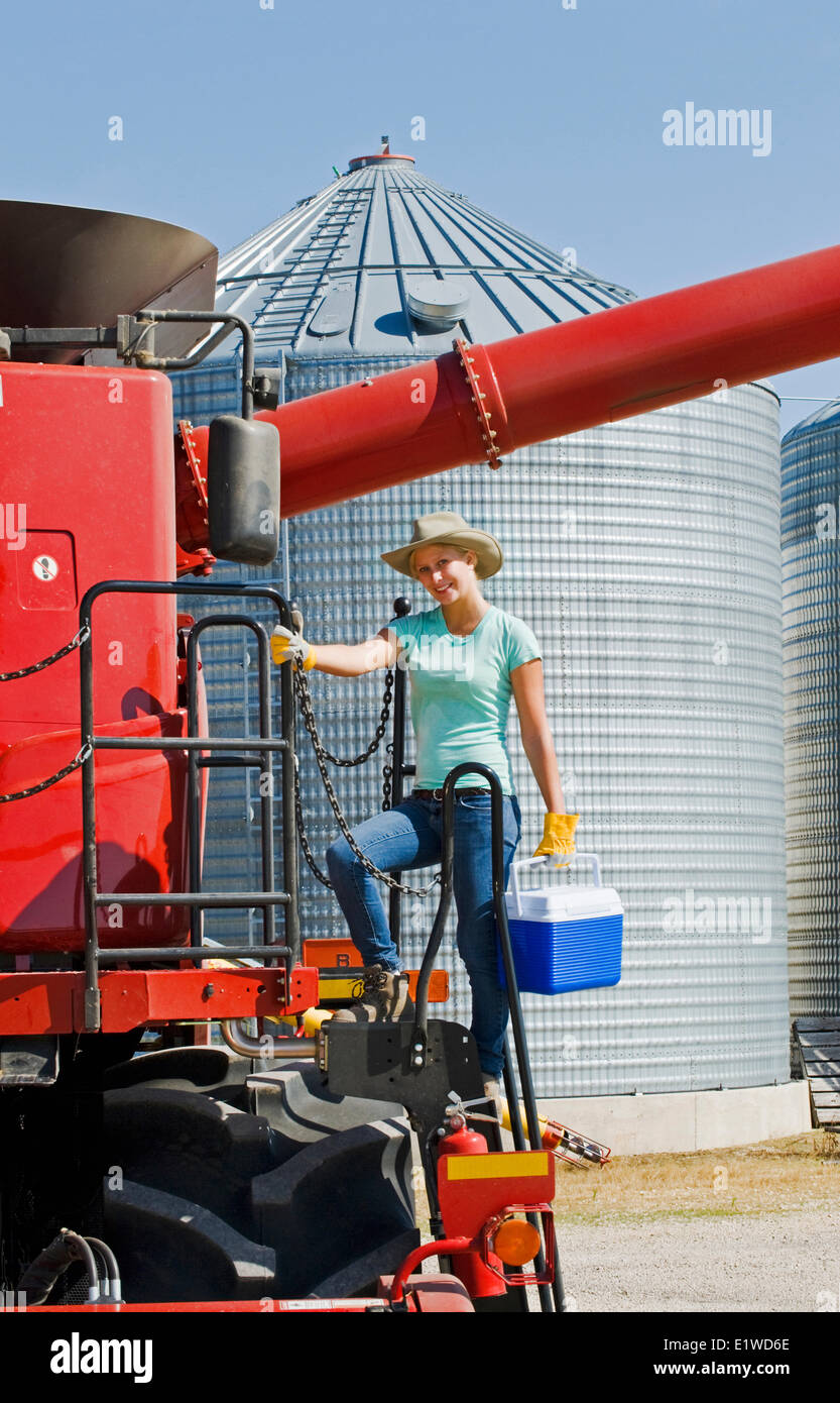 a farm girl on the deck of a combine in a farmyard prepares for a day ...