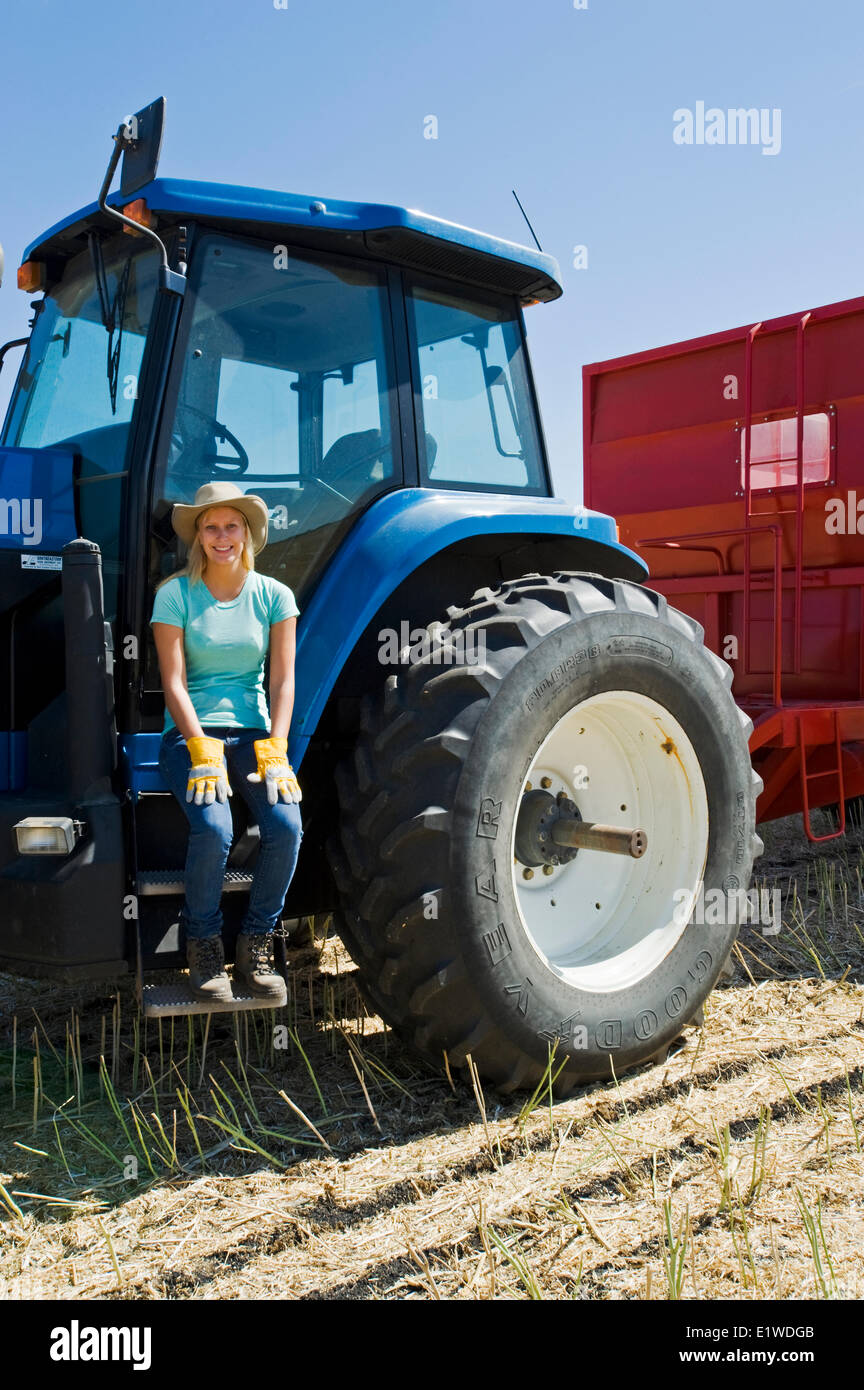 a farm girl on the deck of a tractor with grain wagon during the ...