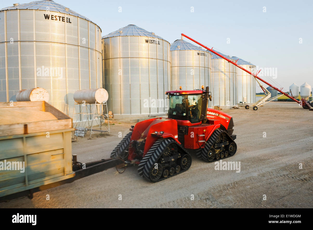 a tractor and grain wagon loaded with wheat passes grain storage bins ...