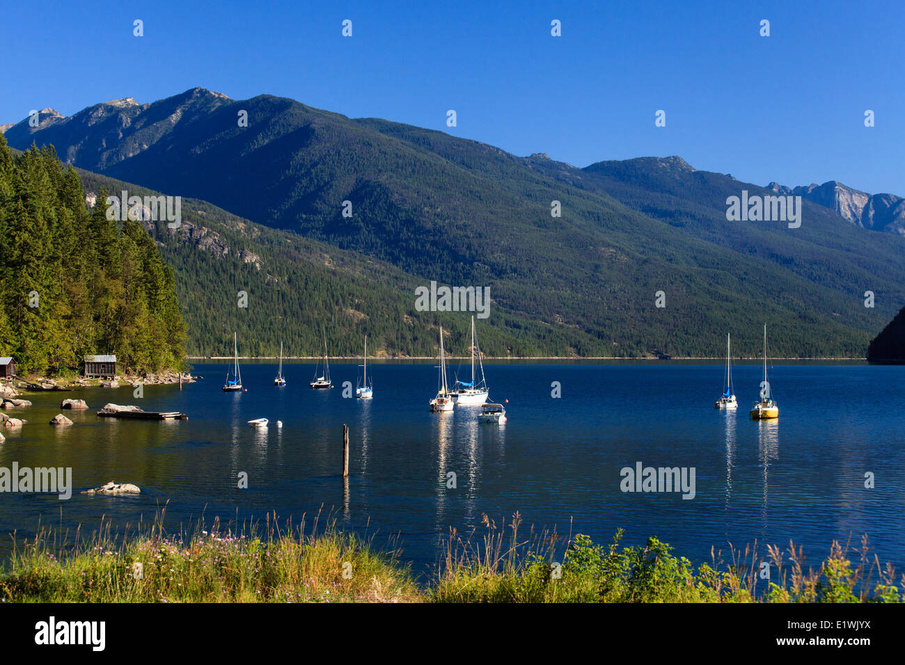 Boats floating on Slocan Lake with the Valhalla Range in the background ...