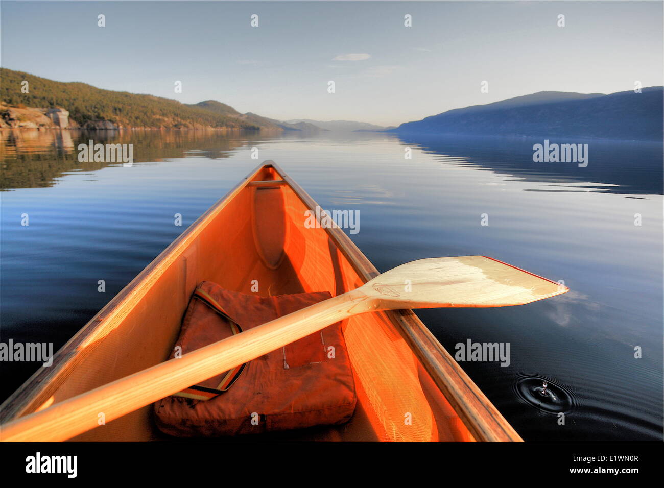 canoe on Okanagan Lake with paddle resting on it and a water droplet in ...