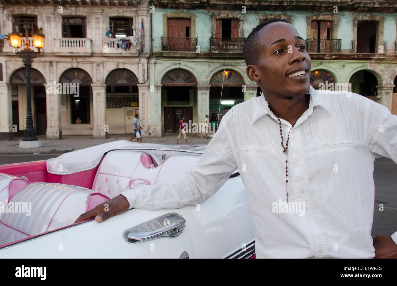 Young cuban driver and classic american car and old building facades ...