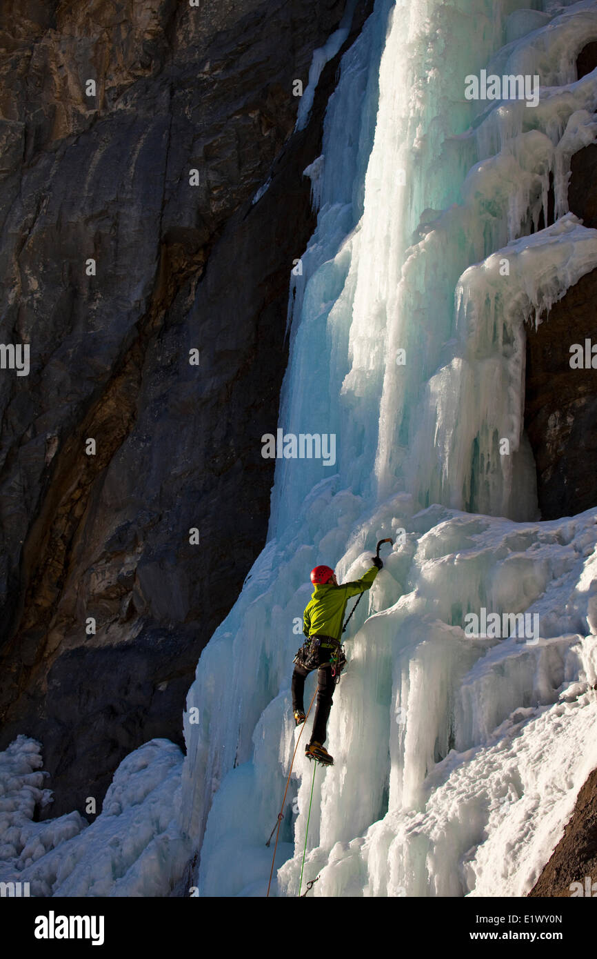 A male ice climber works his way the beautiful sunny ice climb called ...