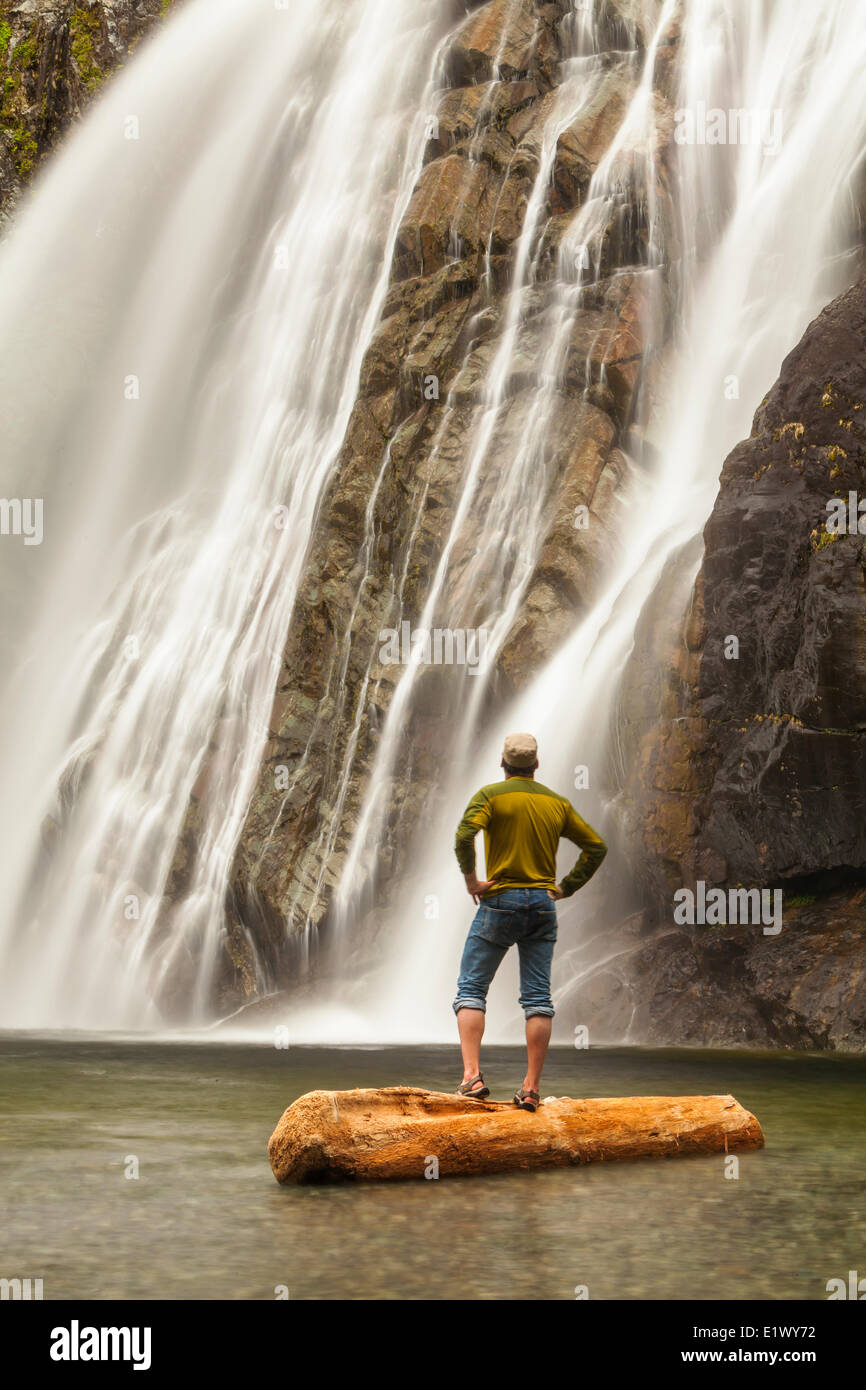 A mature man watches a cascading waterfall while relaxing near ...
