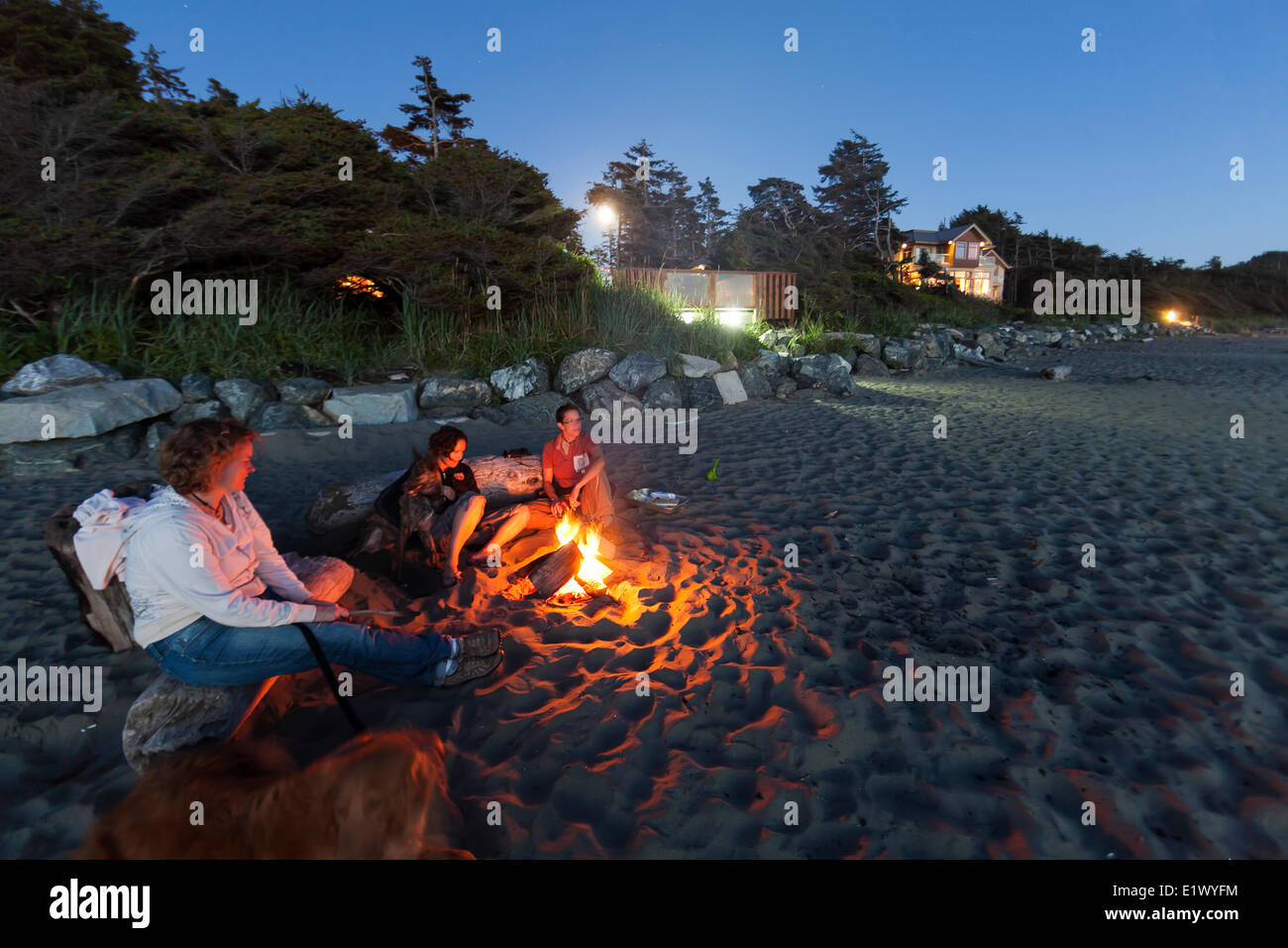 Three girlfriends relax around a fire at Cox Bay near Tofino. Pacific ...