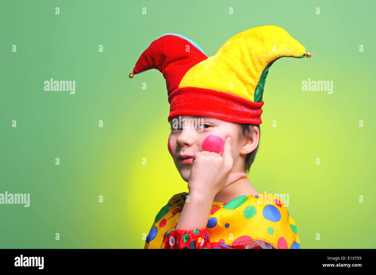 Boy dressed buffoon (Harlequin / Clown/Buffoon) on a bright background ...