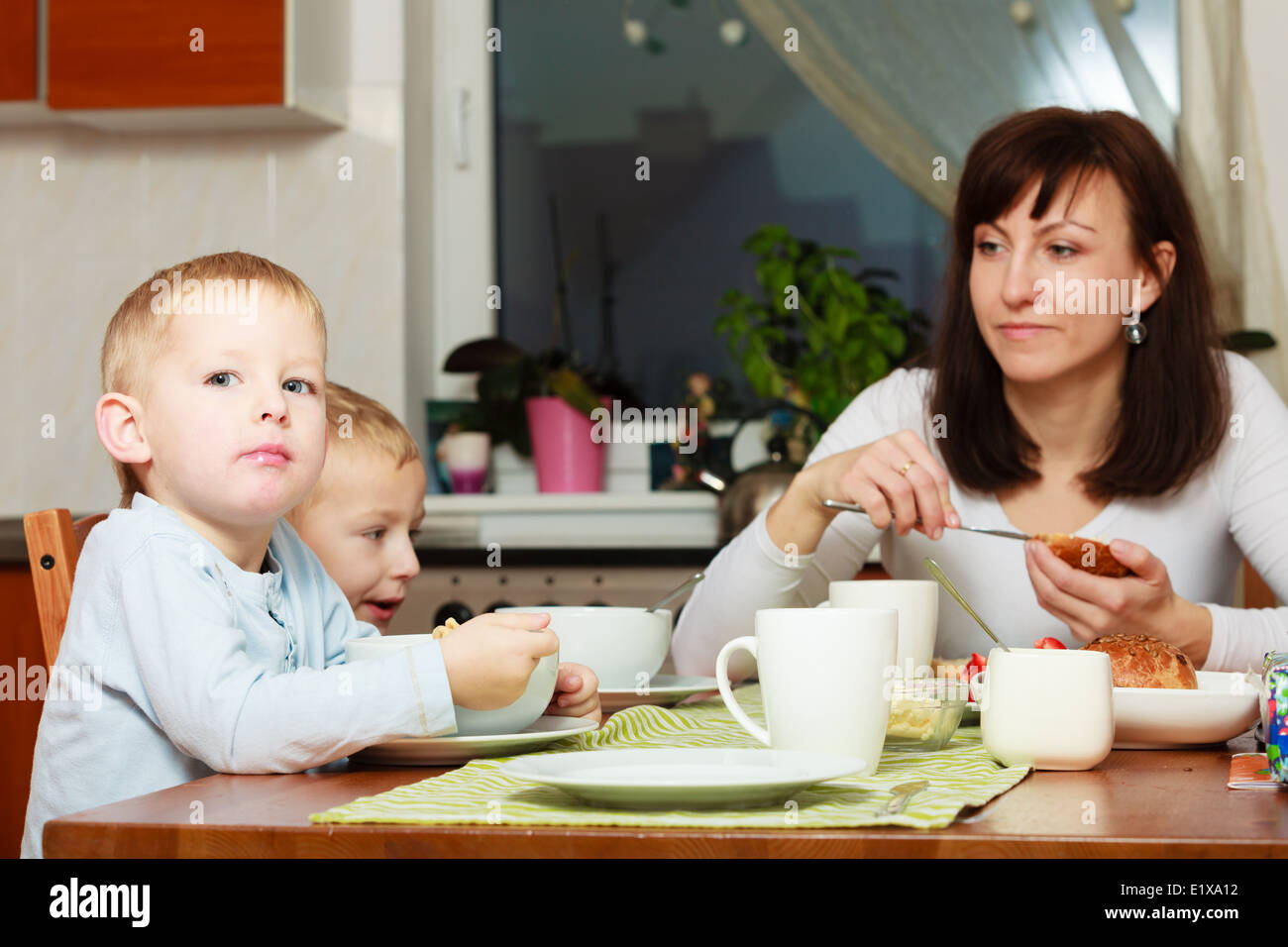 Family mother and two blond brothers boys kids children eating corn ...