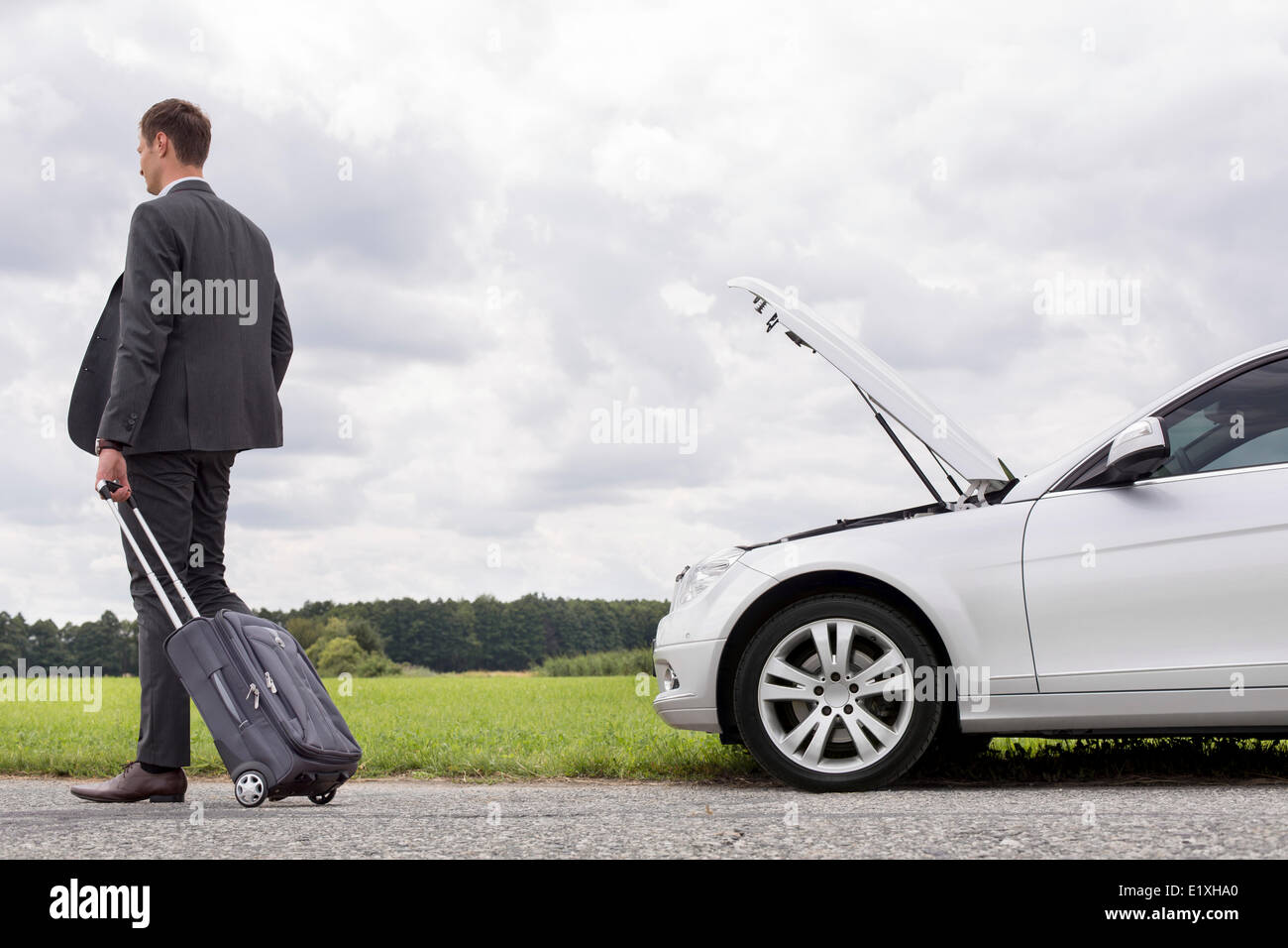 Full length rear view of young businessman with luggage leaving broken ...