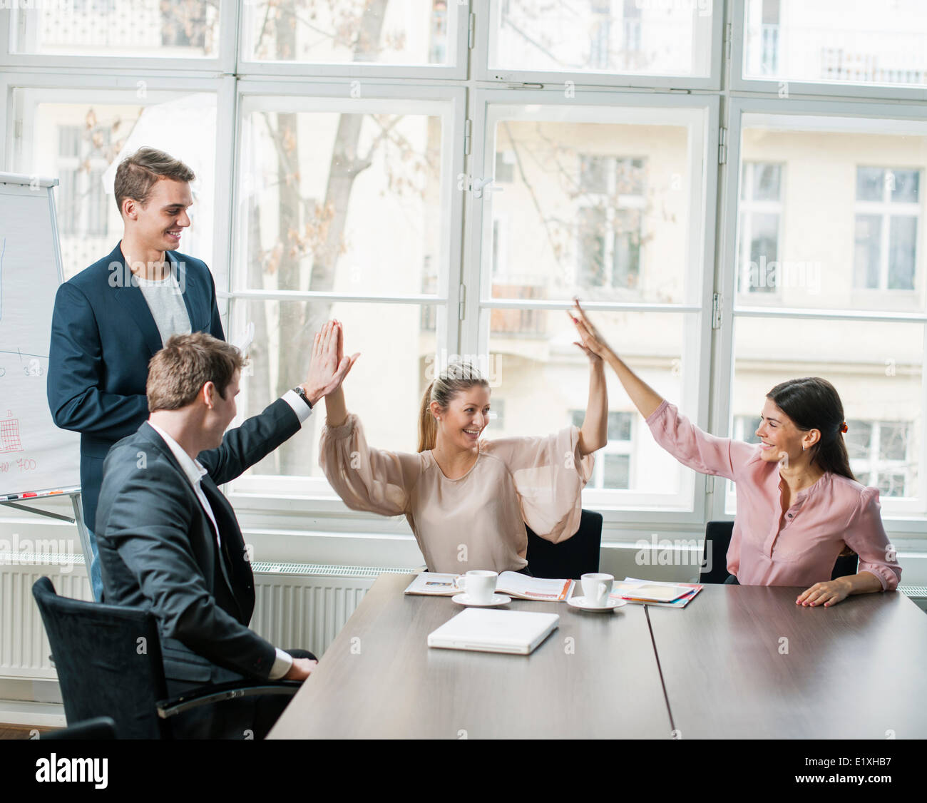 Young business team doing high five at conference table Stock Photo - Alamy