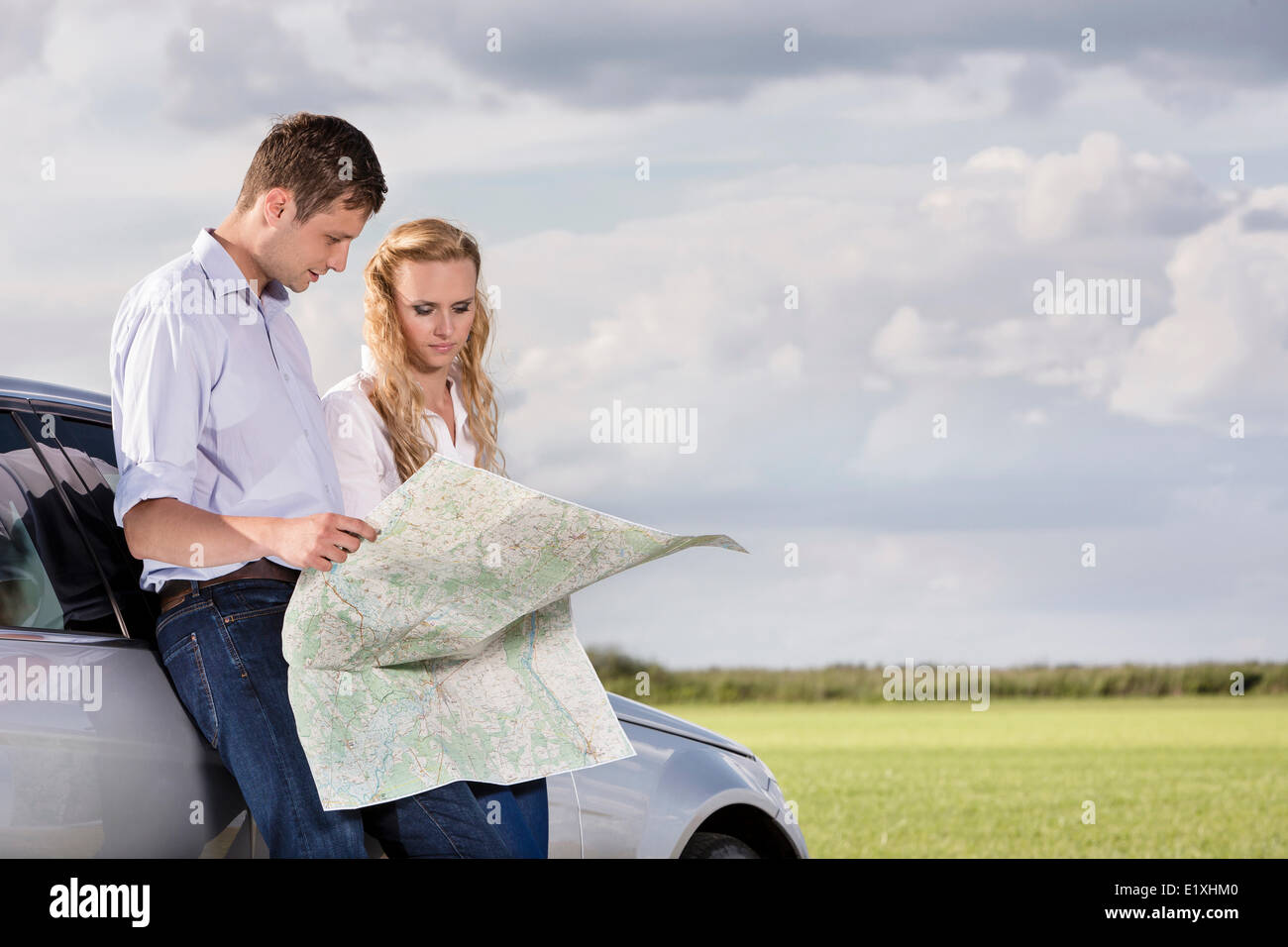Couple reading map while leaning on car at countryside Stock Photo - Alamy