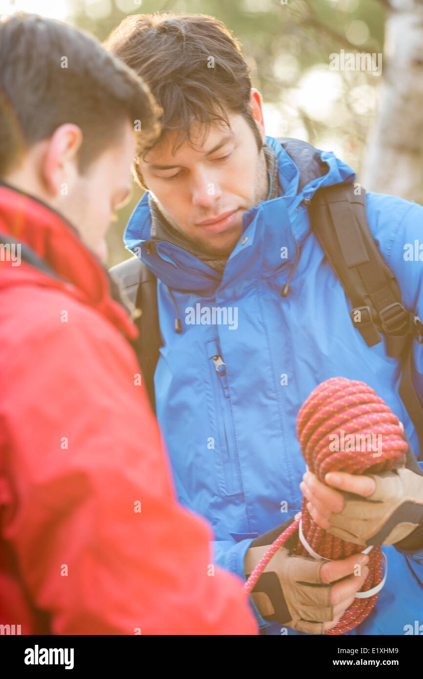 Male hikers looking at rope in forest Stock Photo - Alamy