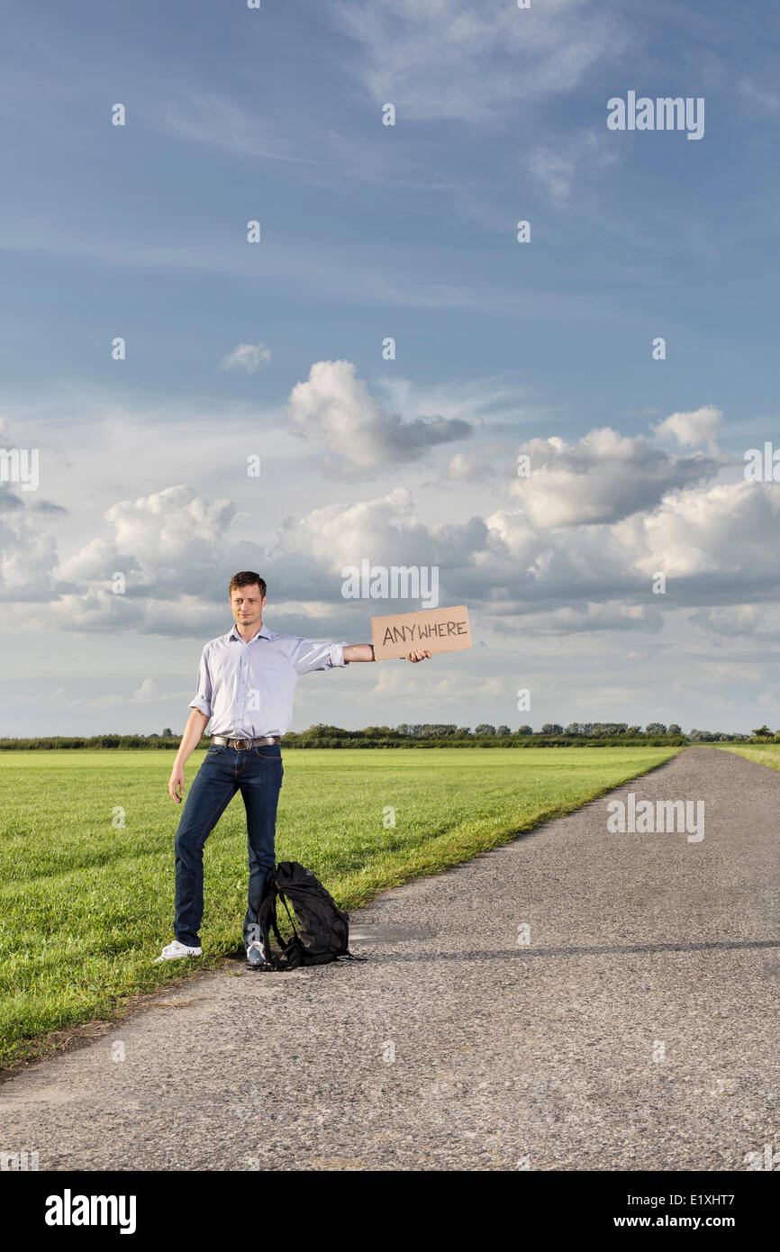 Full length of young man holding anywhere sign on empty road Stock ...