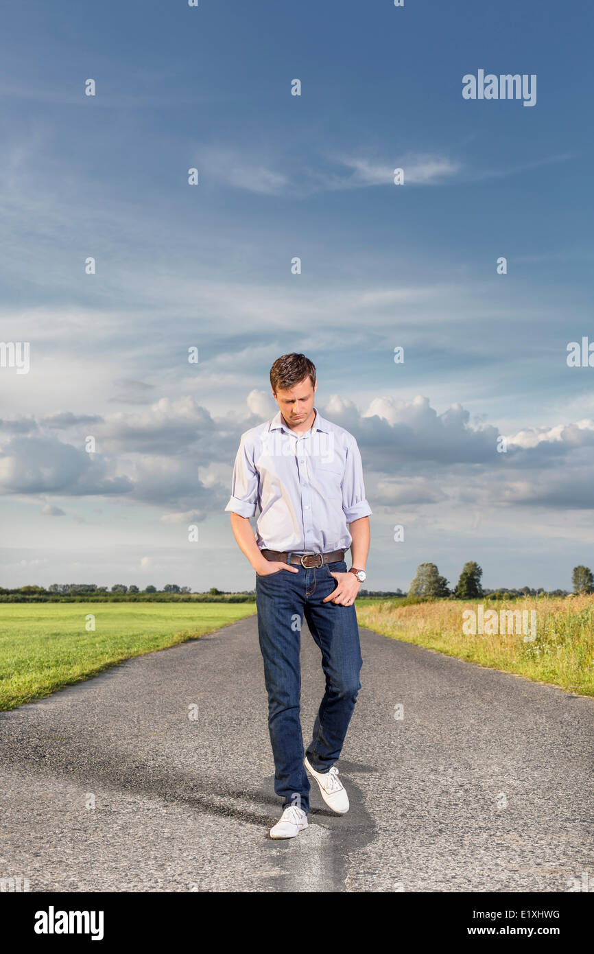 Full length of young man walking on empty rural road Stock Photo - Alamy