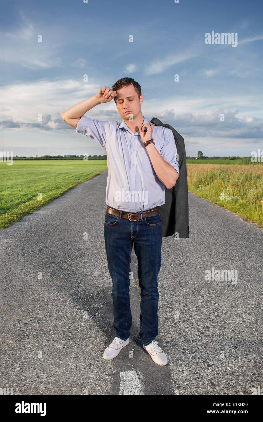Full length of tired young man standing on empty rural road Stock Photo ...
