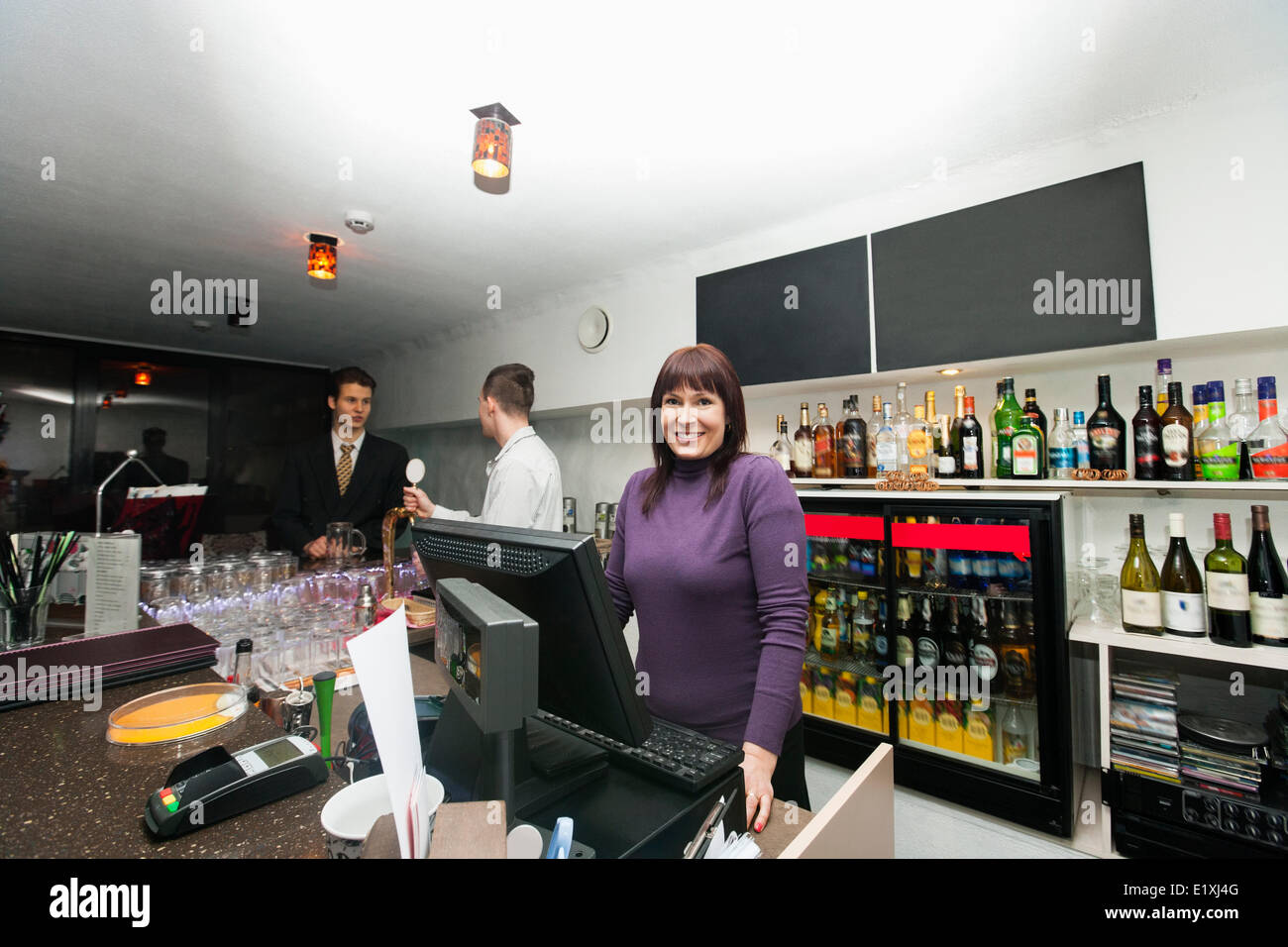 Portrait of female cashier with manager and bartender at bar counter ...