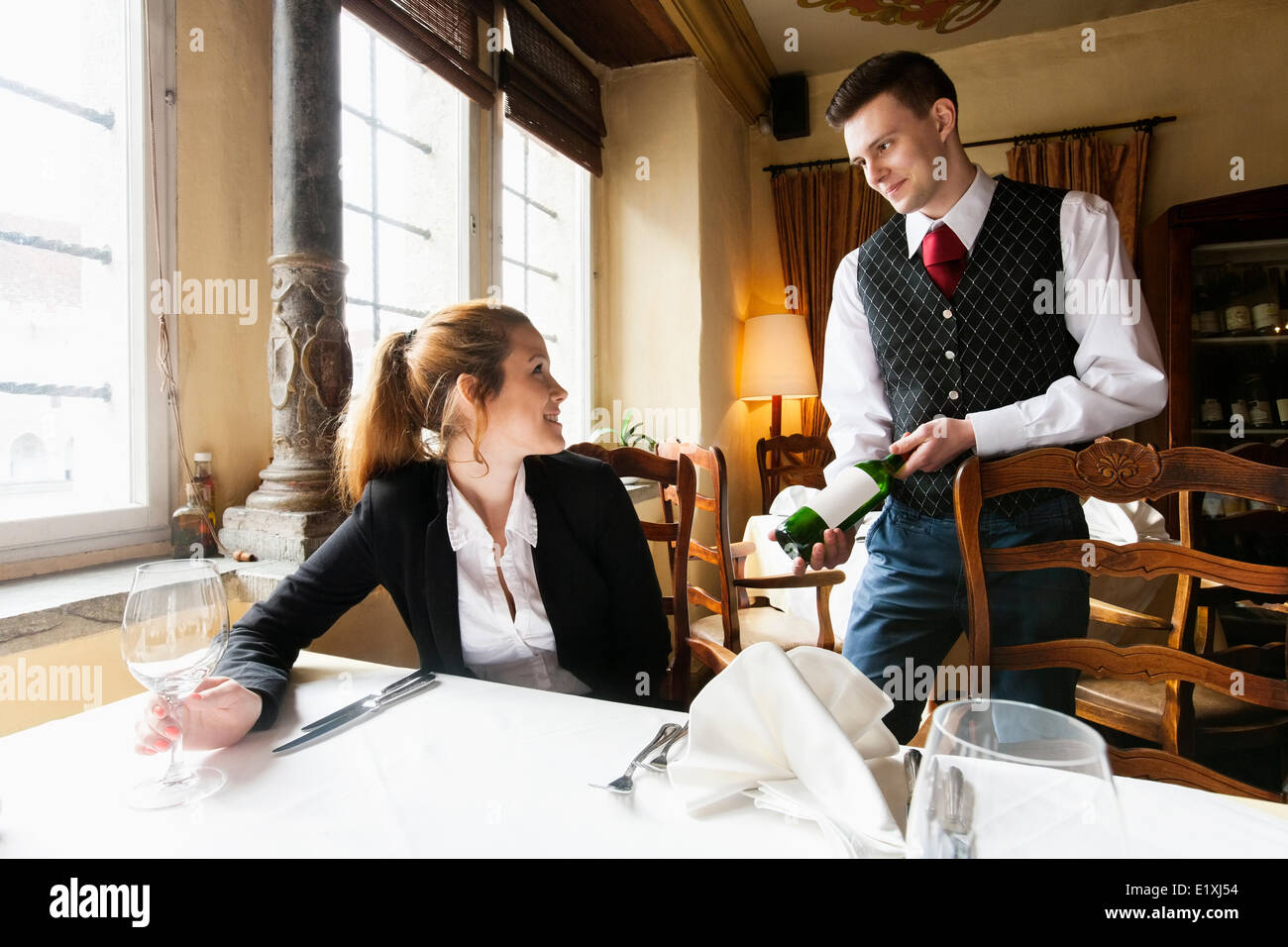 Waiter showing wine bottle to female customer at table in restaurant ...