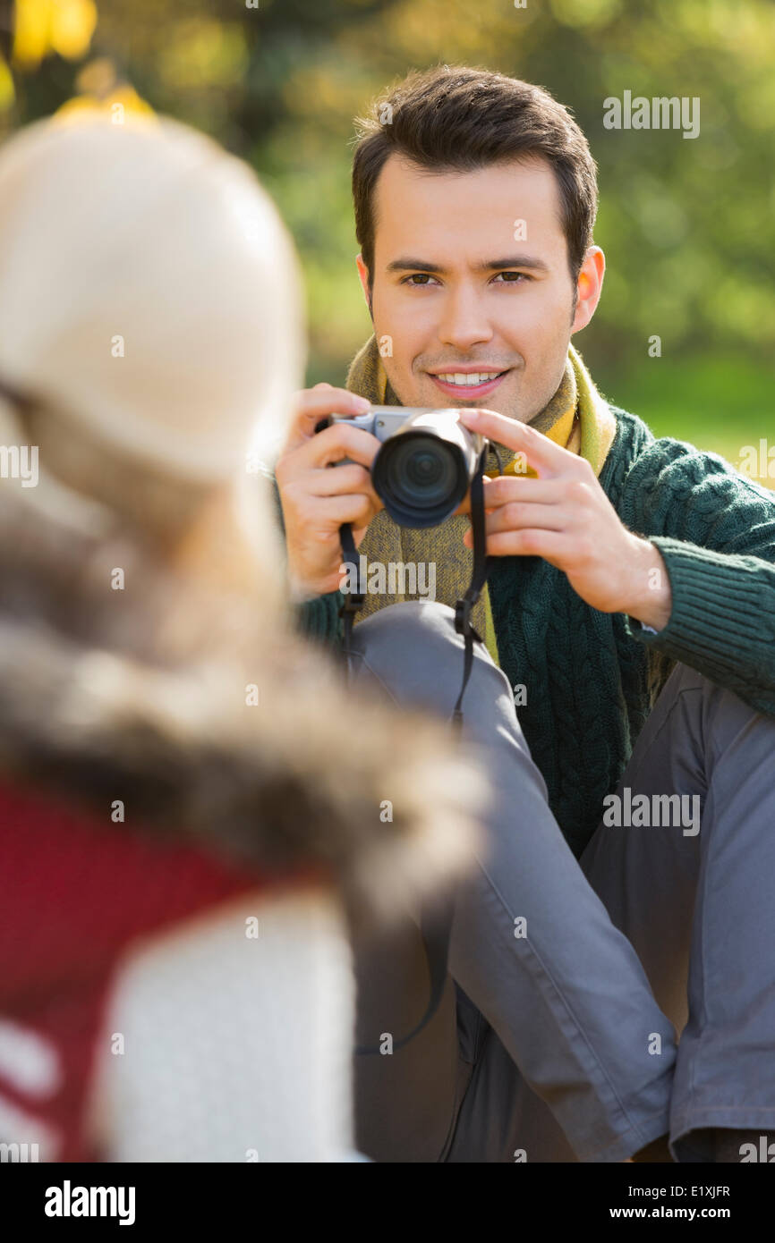 Smiling young man photographing woman in park Stock Photo - Alamy