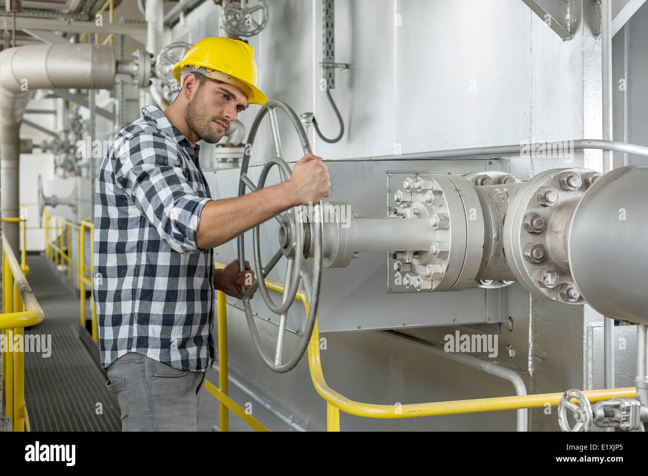 Industrial worker turning large valve Stock Photo - Alamy