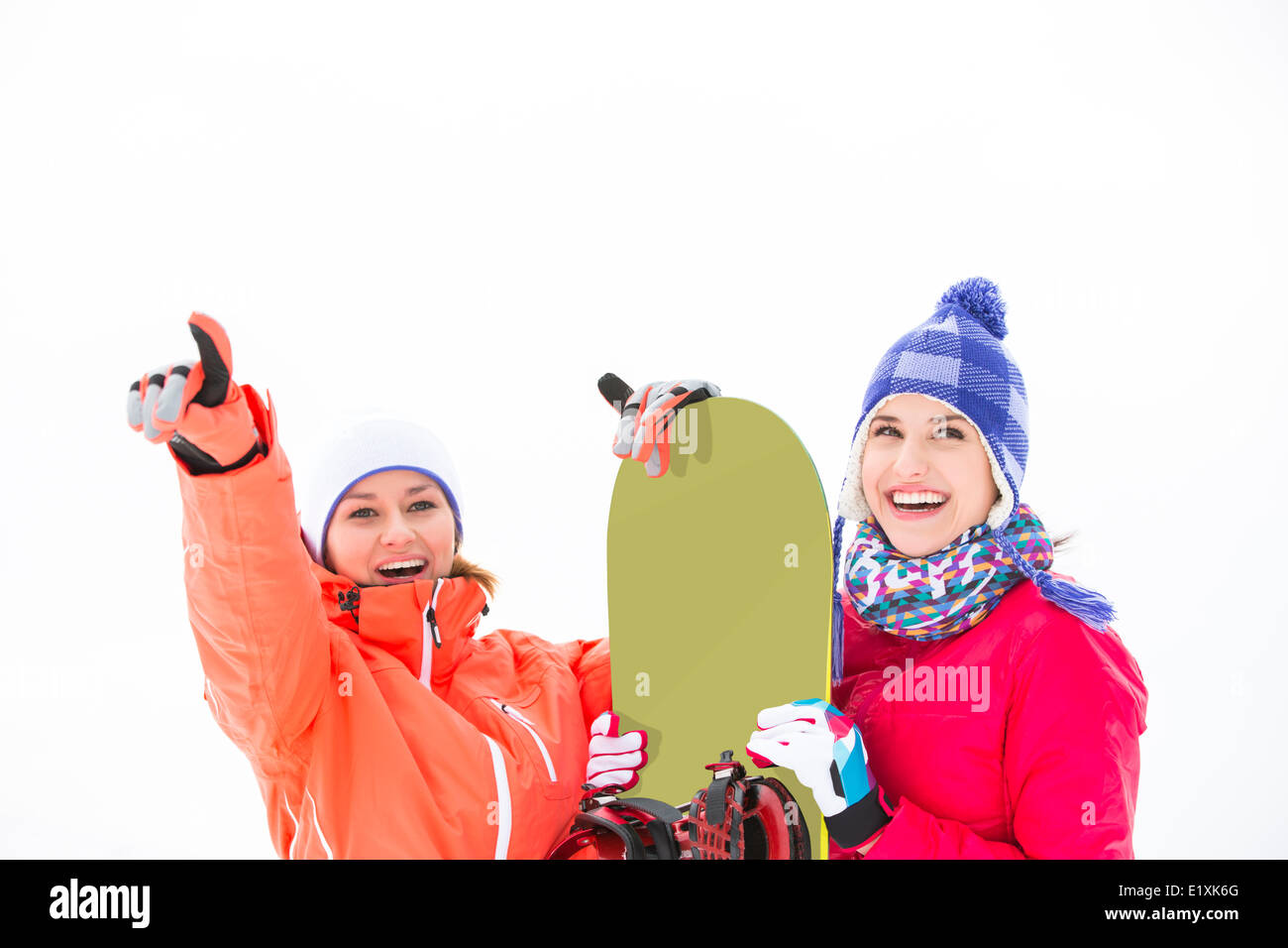 Smiling female friends with snowboard outdoors Stock Photo - Alamy