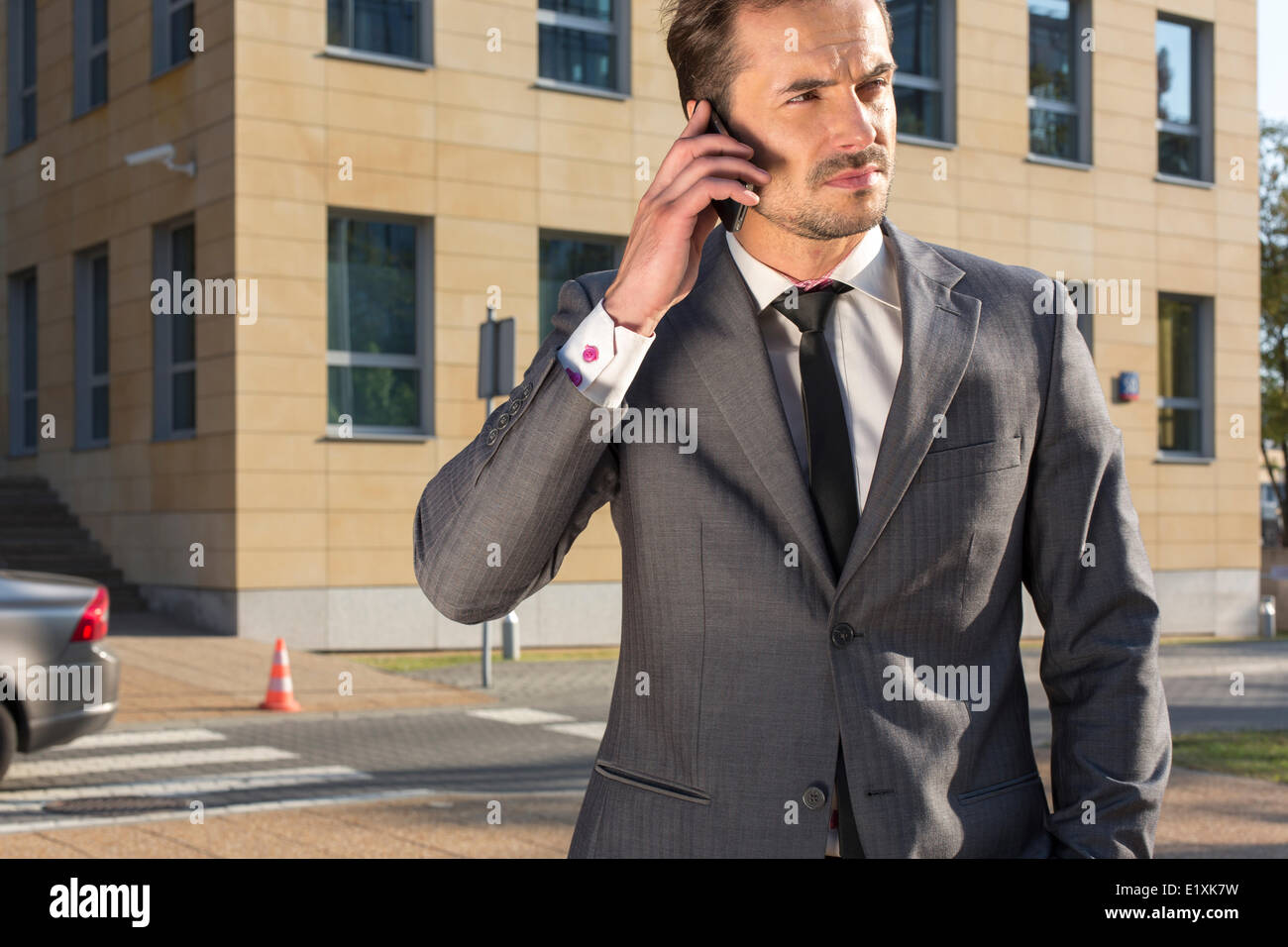 Young businessman using cell phone against office building Stock Photo ...