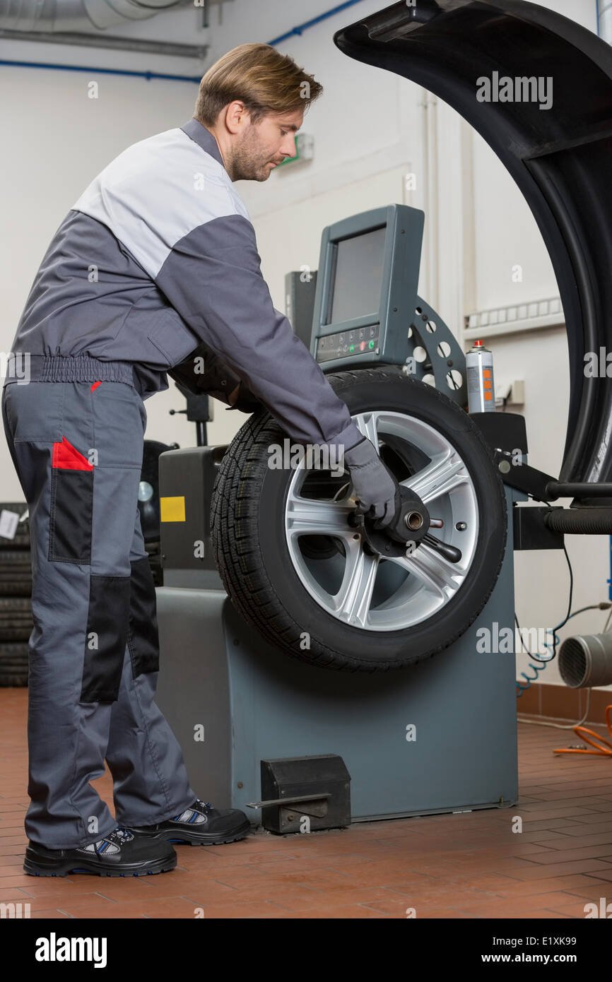 Side view of male mechanic repairing car's wheel in workshop Stock ...