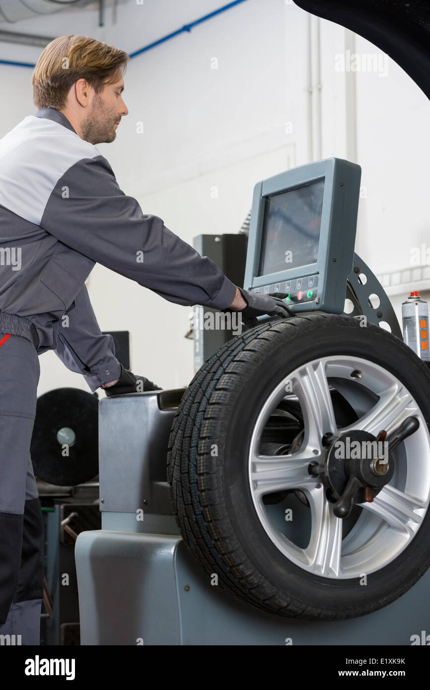 Side view of mid adult male mechanic repairing car's wheel in workshop ...