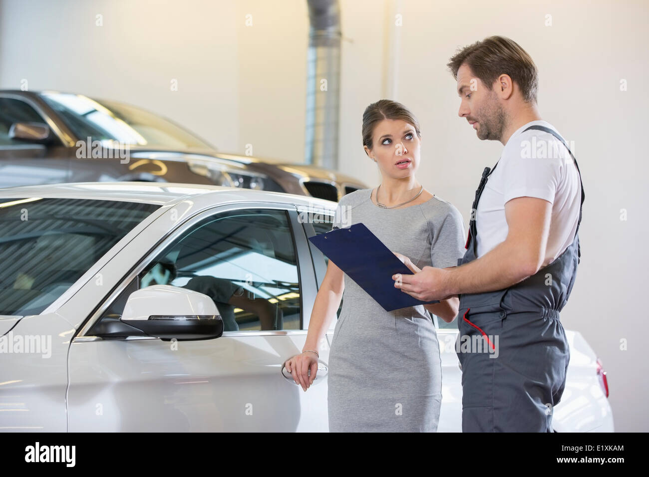 Repairman holding clipboard while conversing with female customer in ...