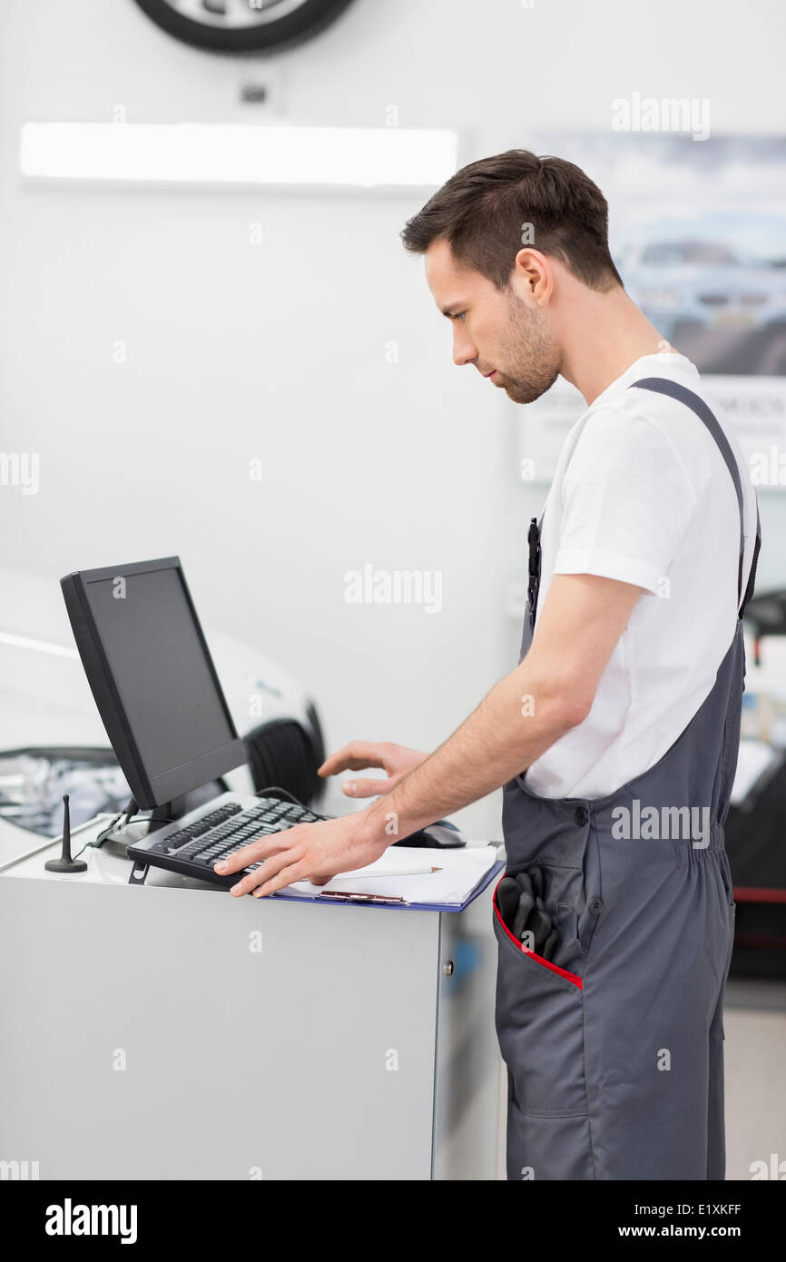Side view of automobile mechanic using computer in workshop Stock Photo ...