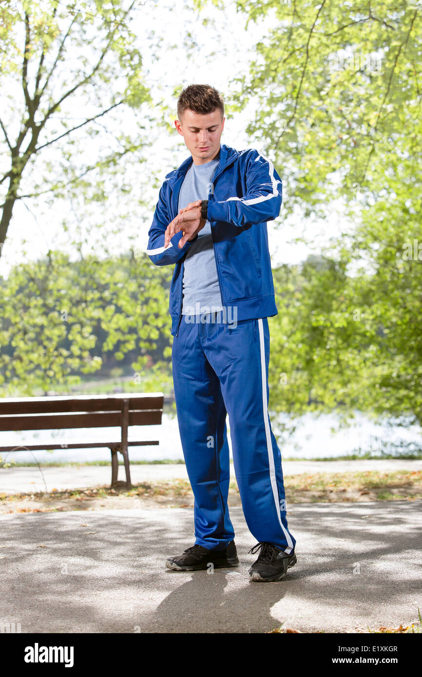 Full length of fit man checking time on path in park Stock Photo - Alamy