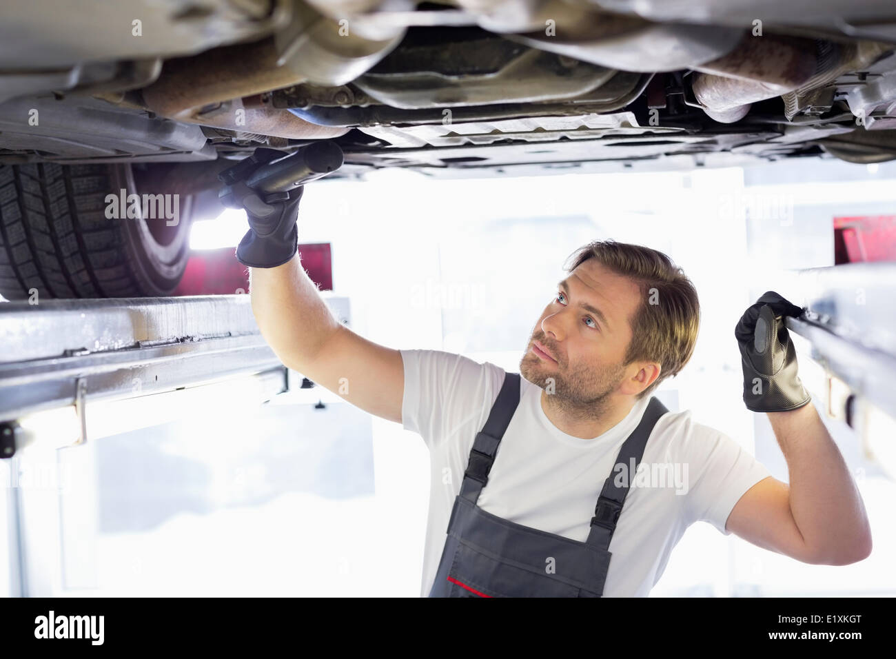 Male repair worker examining car in workshop Stock Photo - Alamy