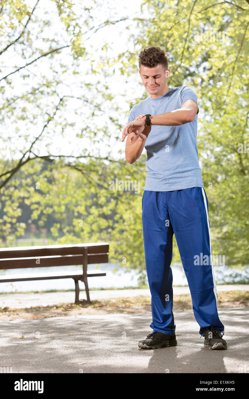 Full length of fit man checking time in park Stock Photo - Alamy