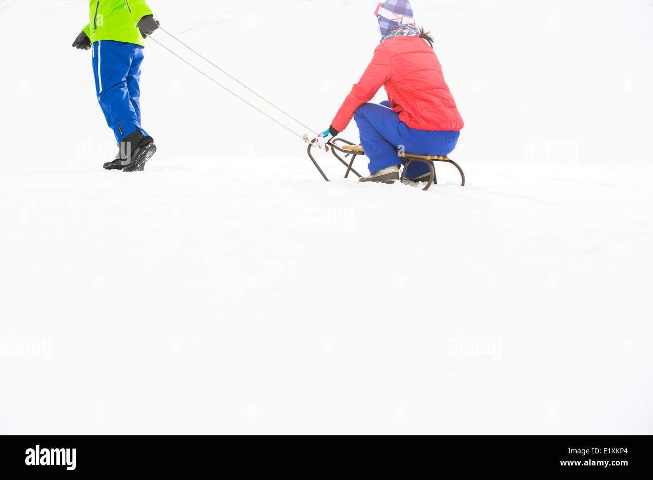 Low section of young man pulling woman on sled Stock Photo - Alamy