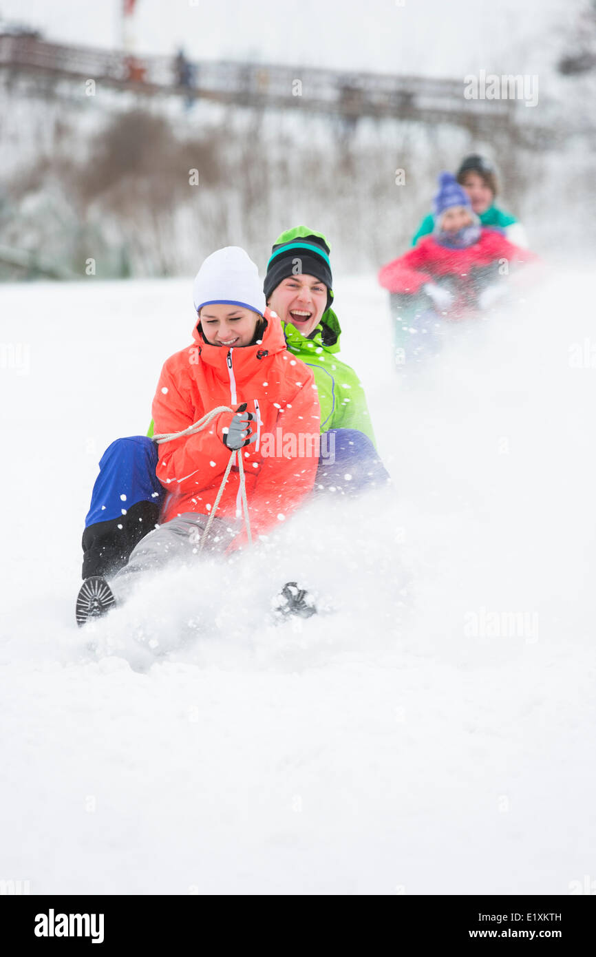Young couple enjoying sled ride on snow covered slope Stock Photo - Alamy