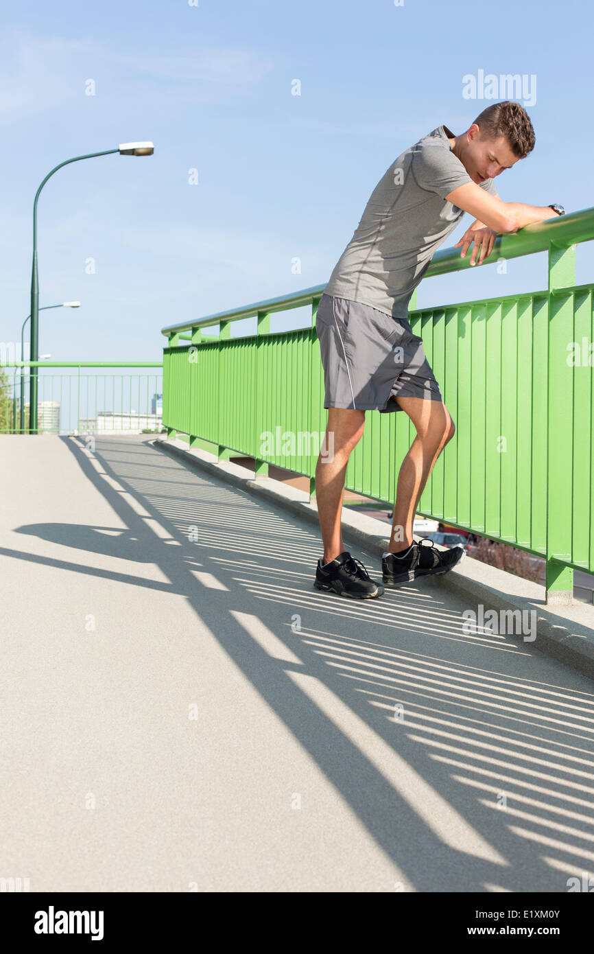 Full length of tired young man leaning on railing after jogging Stock ...