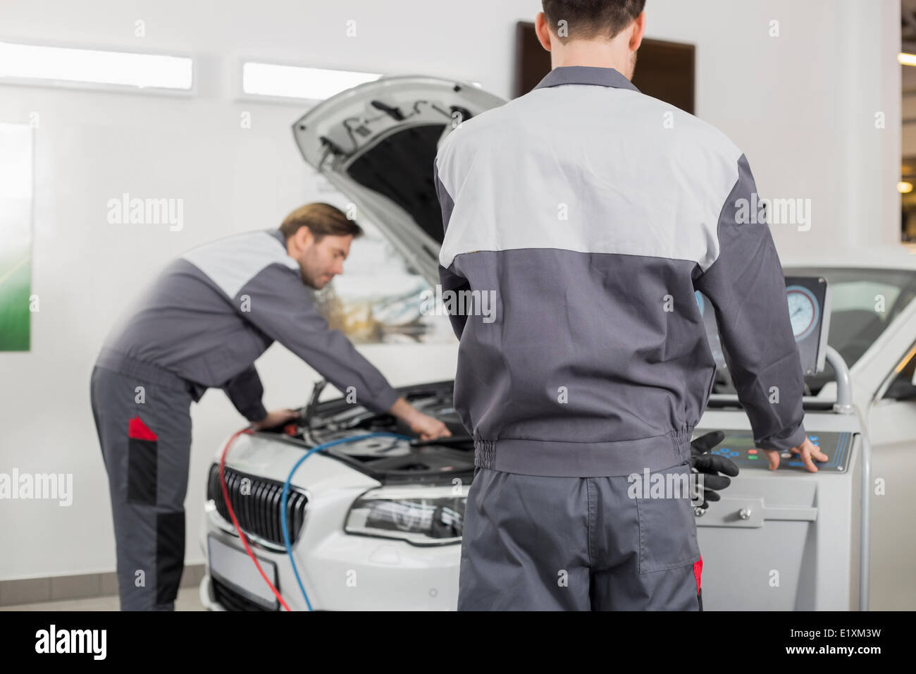 Male maintenance engineers examining car in workshop Stock Photo - Alamy