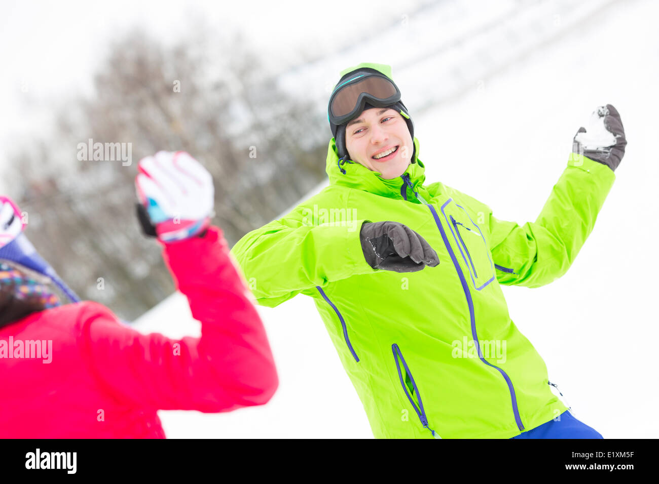 Happy young man throwing snowball towards woman Stock Photo - Alamy