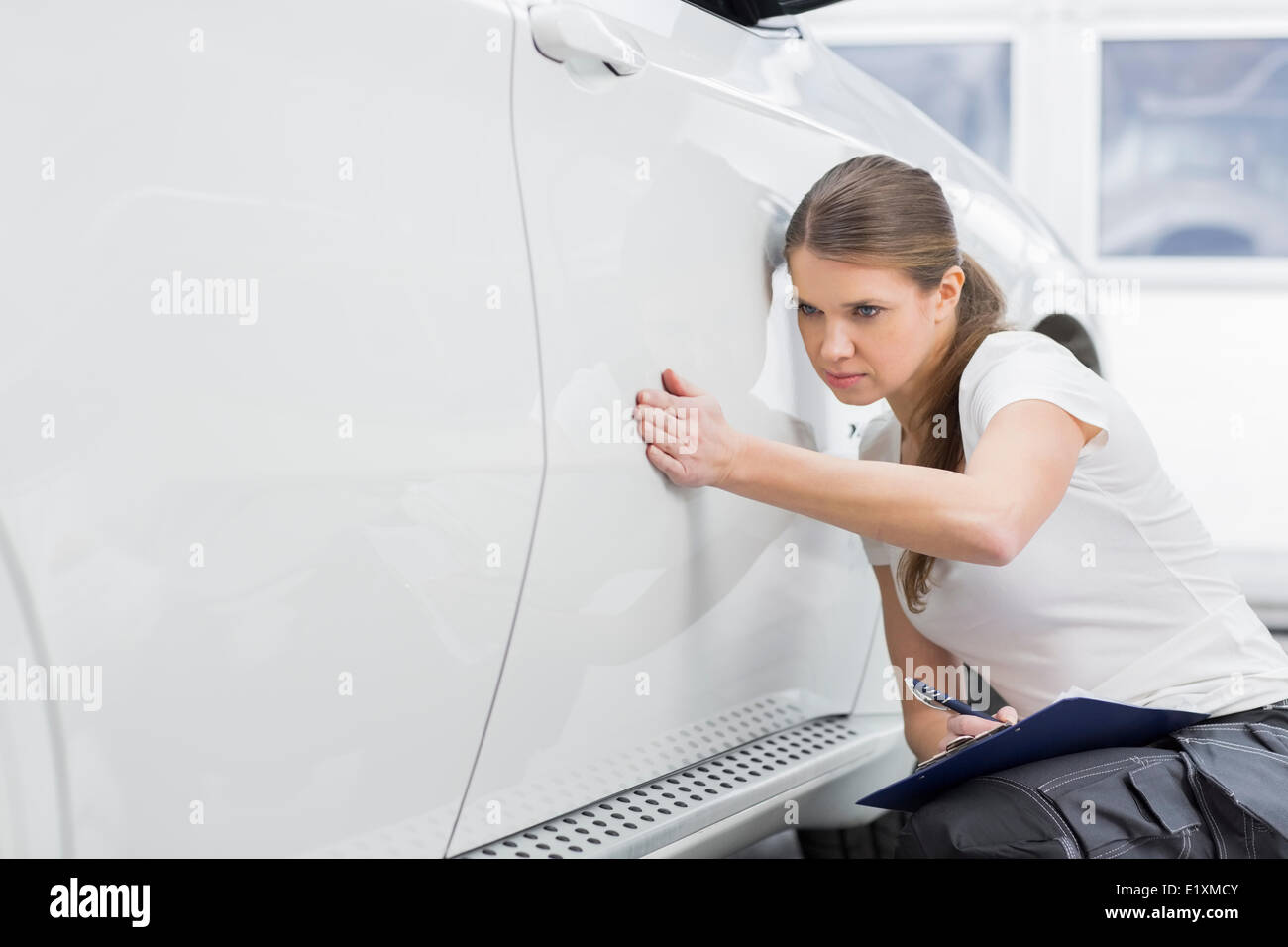 Female maintenance engineer examining car in workshop Stock Photo - Alamy